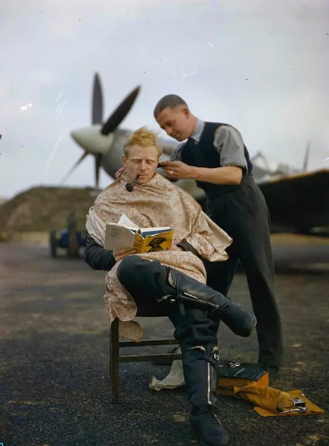 En Raf-pilot som klipper seg mens han leser en bok mellom oppdrag